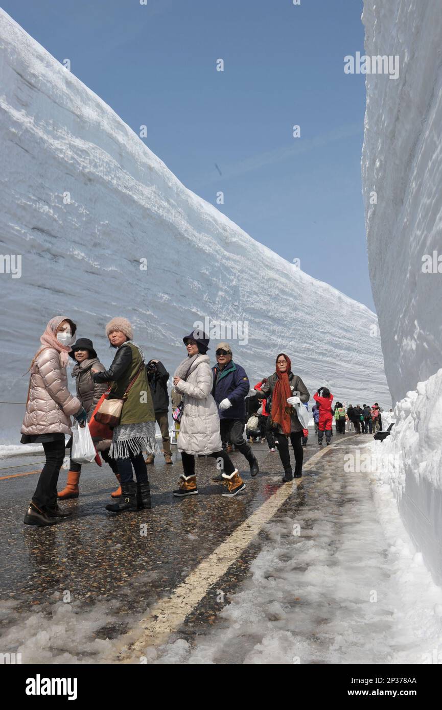Tourists walk along 19-meter-high snow walls at the Tateyama Kurobe ...