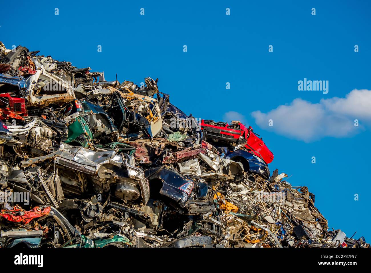 Amidst a messy heap of rusty and crumpled car parts on a junkyard, a ...