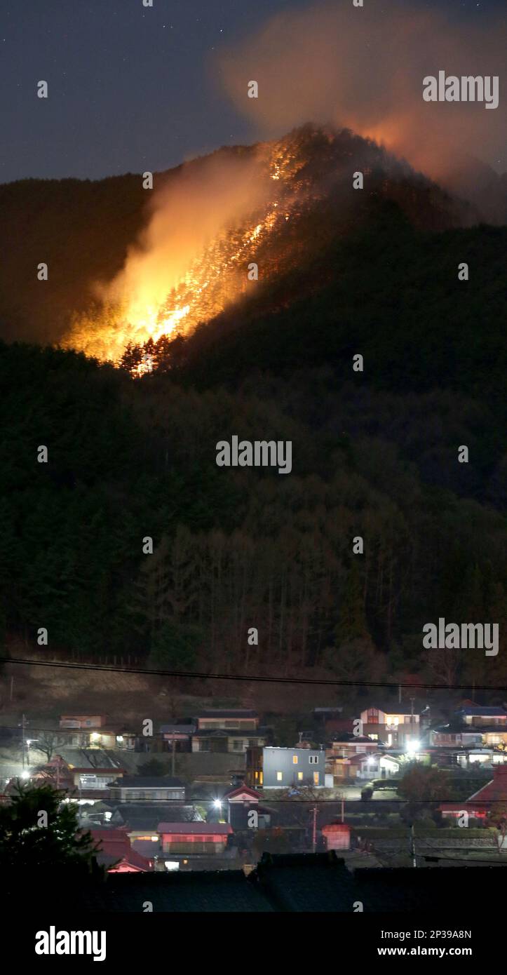 A photo shows smoke and fire from a wildfire on mountains approaching ...