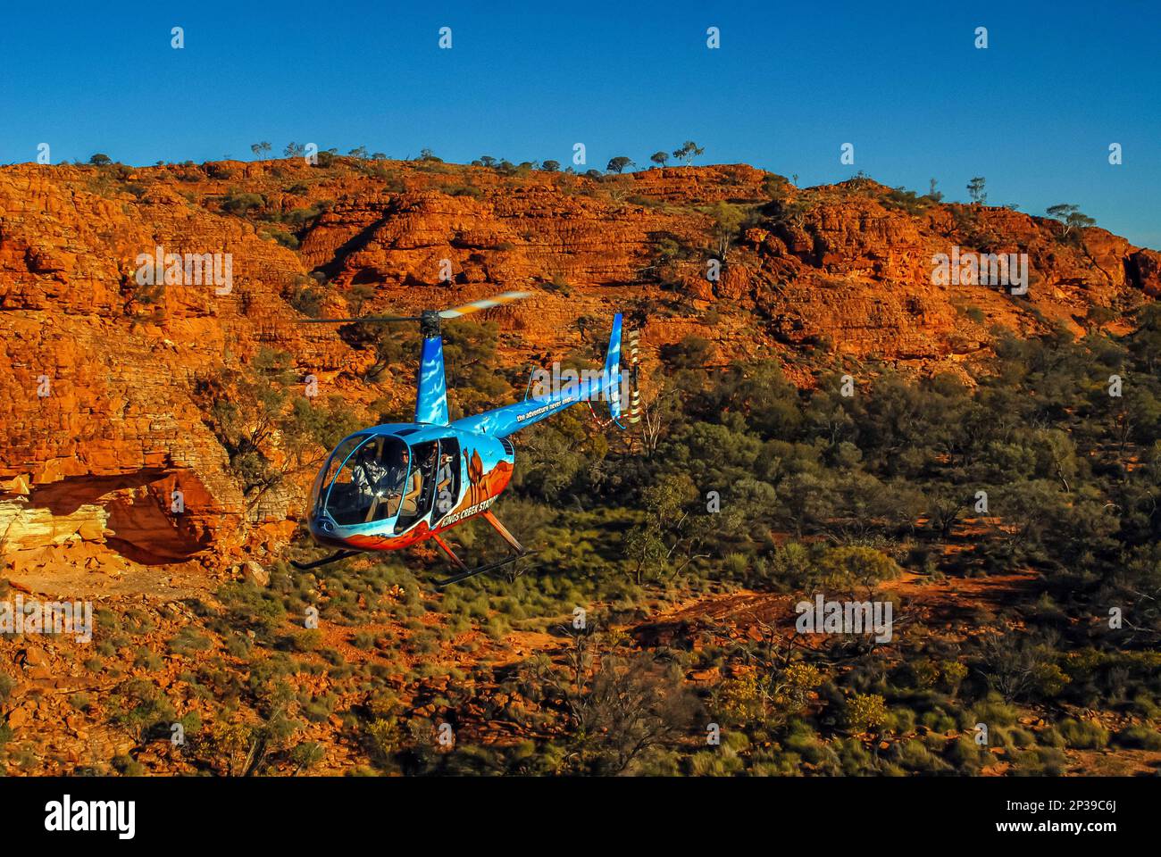 A Robinson R44 Clipper helicopter with open doors, flying tourists over ...