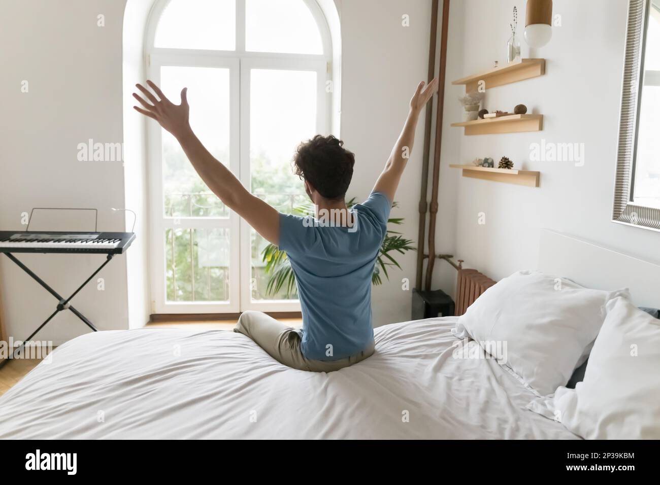 Positive excited young man enjoying good morning in bedroom Stock Photo ...