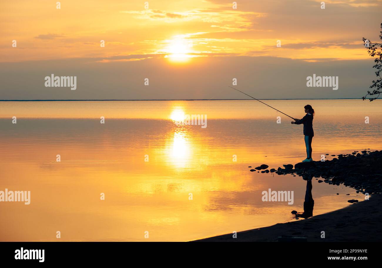 Woman fishing on Fishing rod spinning at sunset background Stock Photo ...