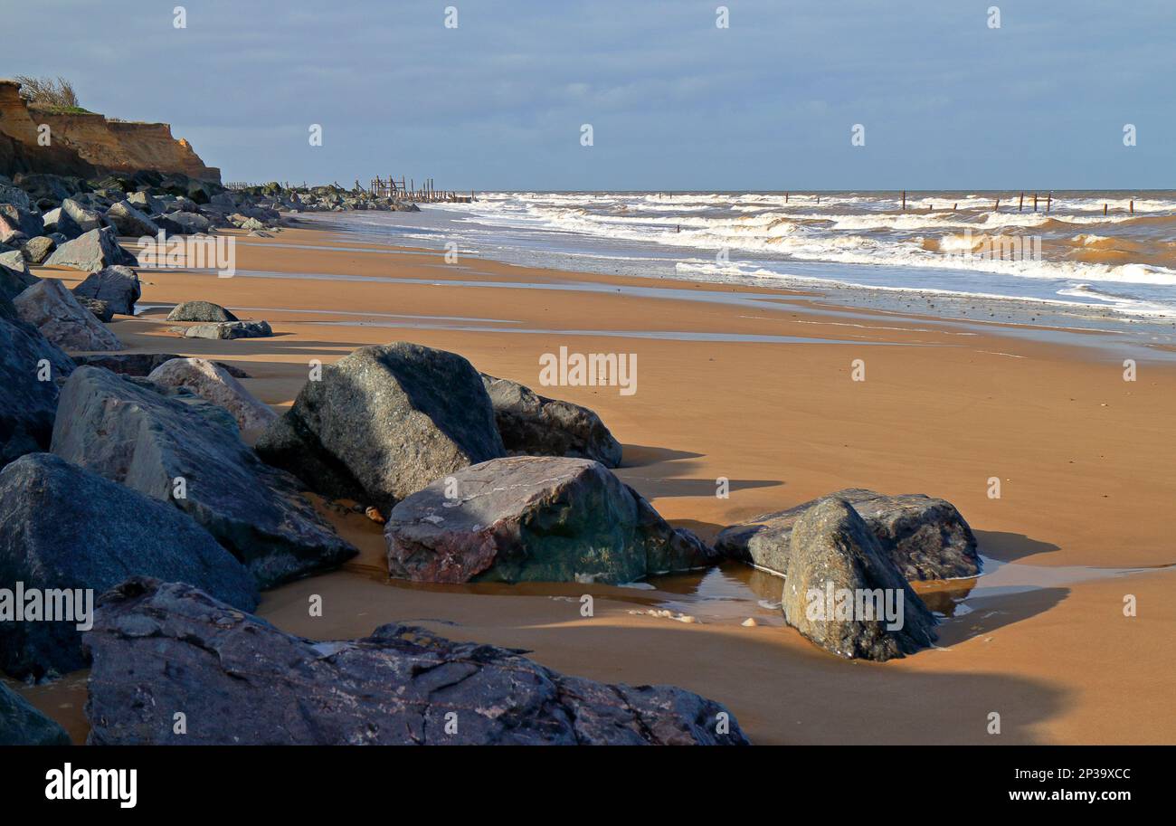A view of the beach in winter with imported rock sea defences and ...