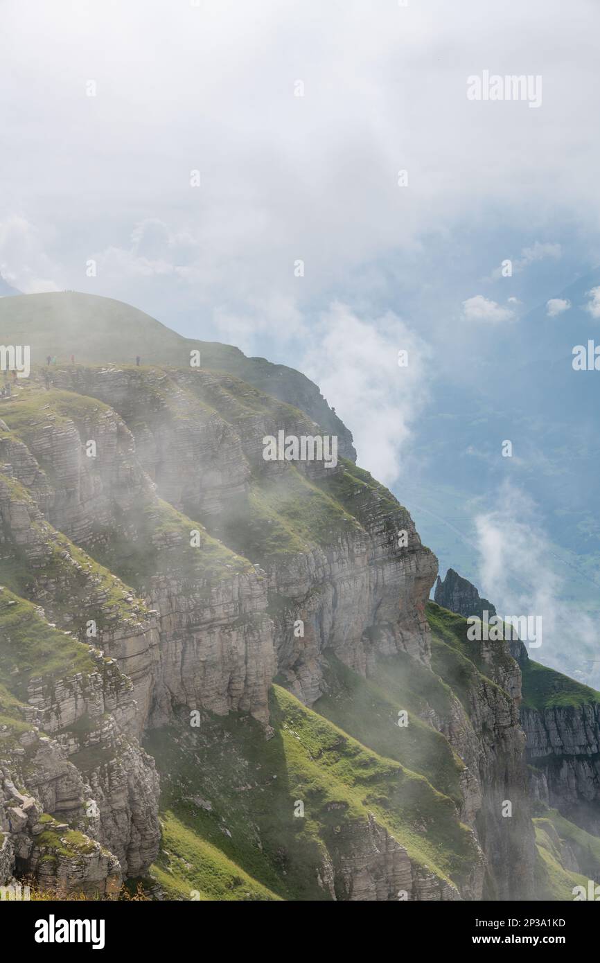 A steep cliff overgrown with grass and hidden by clouds Stock Photo - Alamy
