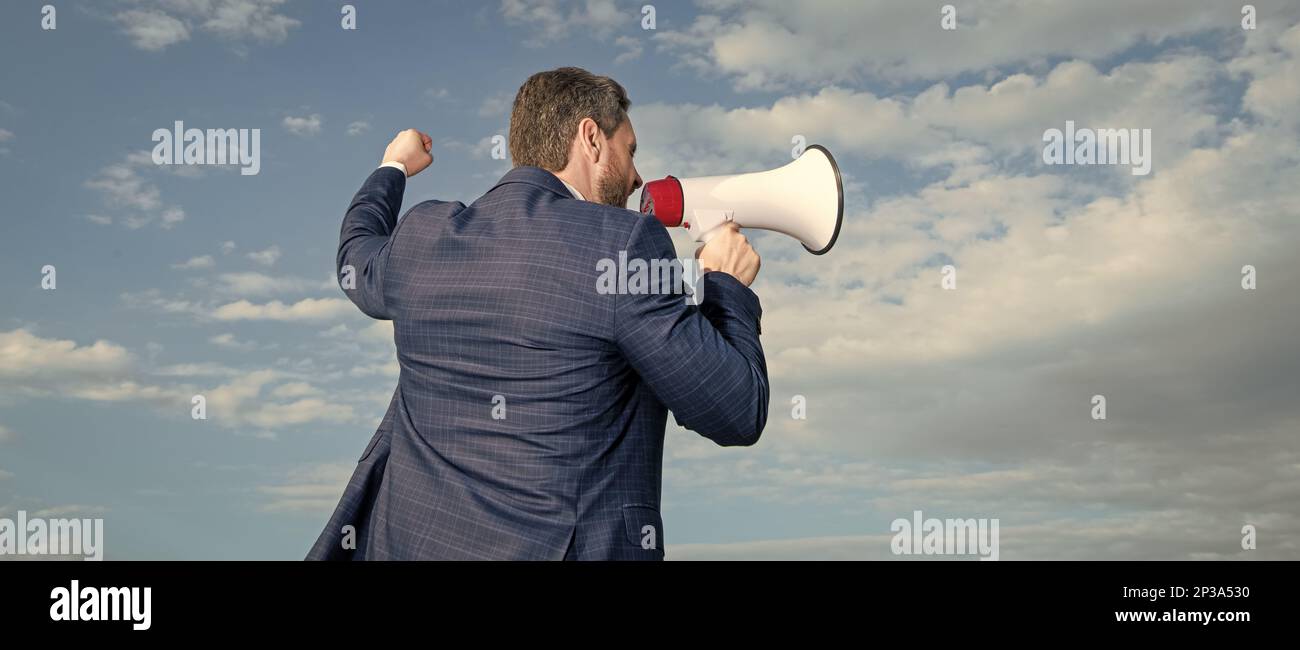 back view of businessman shout in loudspeaker on sky background ...
