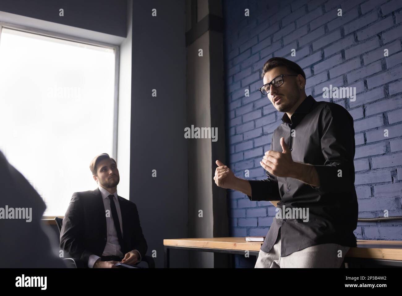 Serious stylish male coach giving workshop to group of employees Stock ...