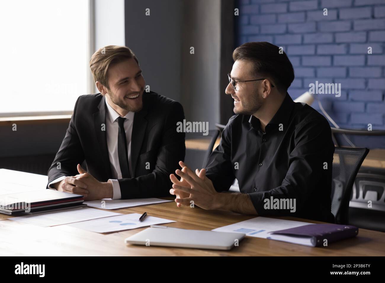 Two cheerful happy business partners men talking at work table Stock ...