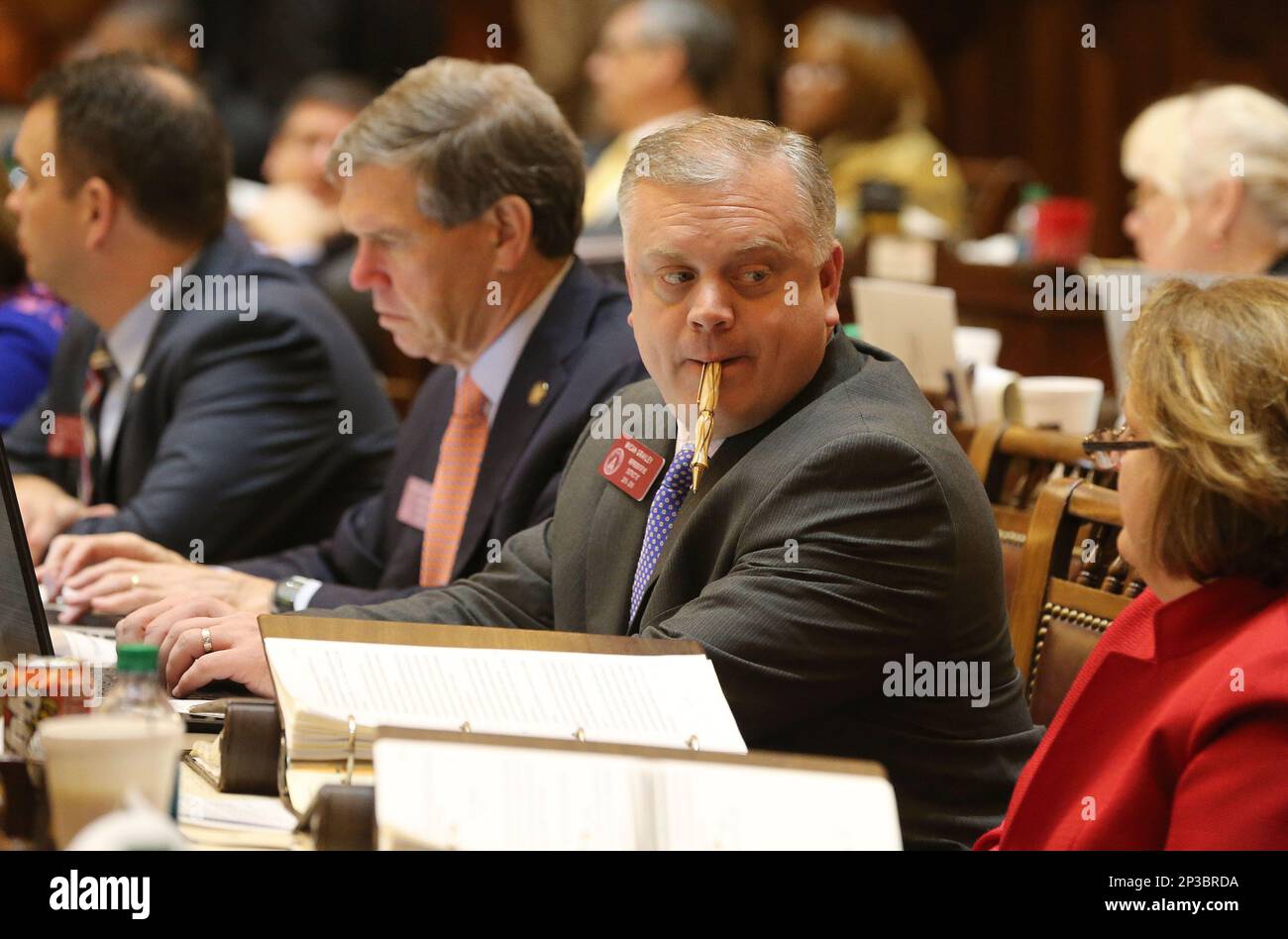 Rep. Micah Gravley, R-Douglasville, types with a pen in his mouth as ...