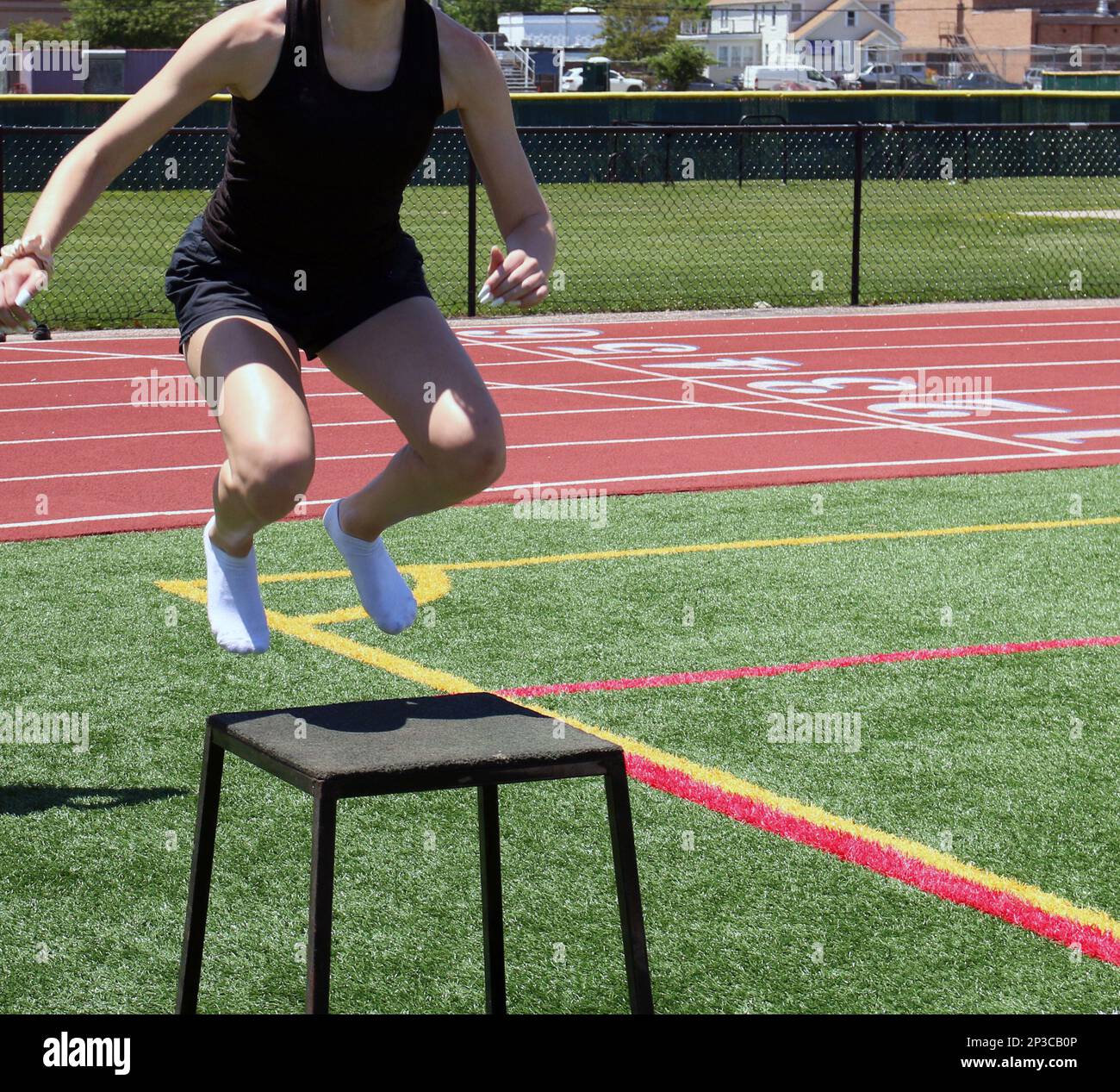 Front view of a Caucasian women wearing black clothing jumping on to a ...