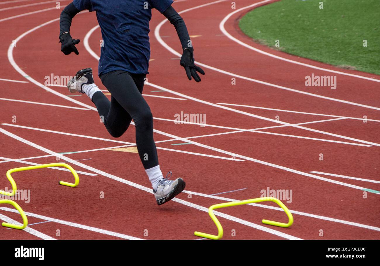 A high shool track and field runner running over yellow six inch ...