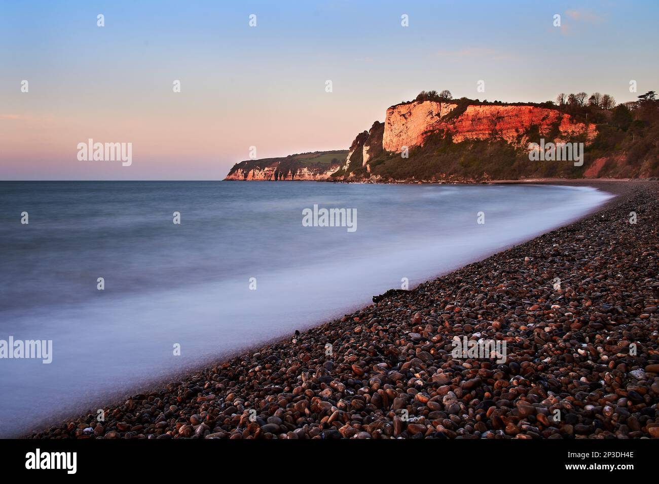 Long exposure of waves lapping on pebble beach in front of chalk cliffs ...