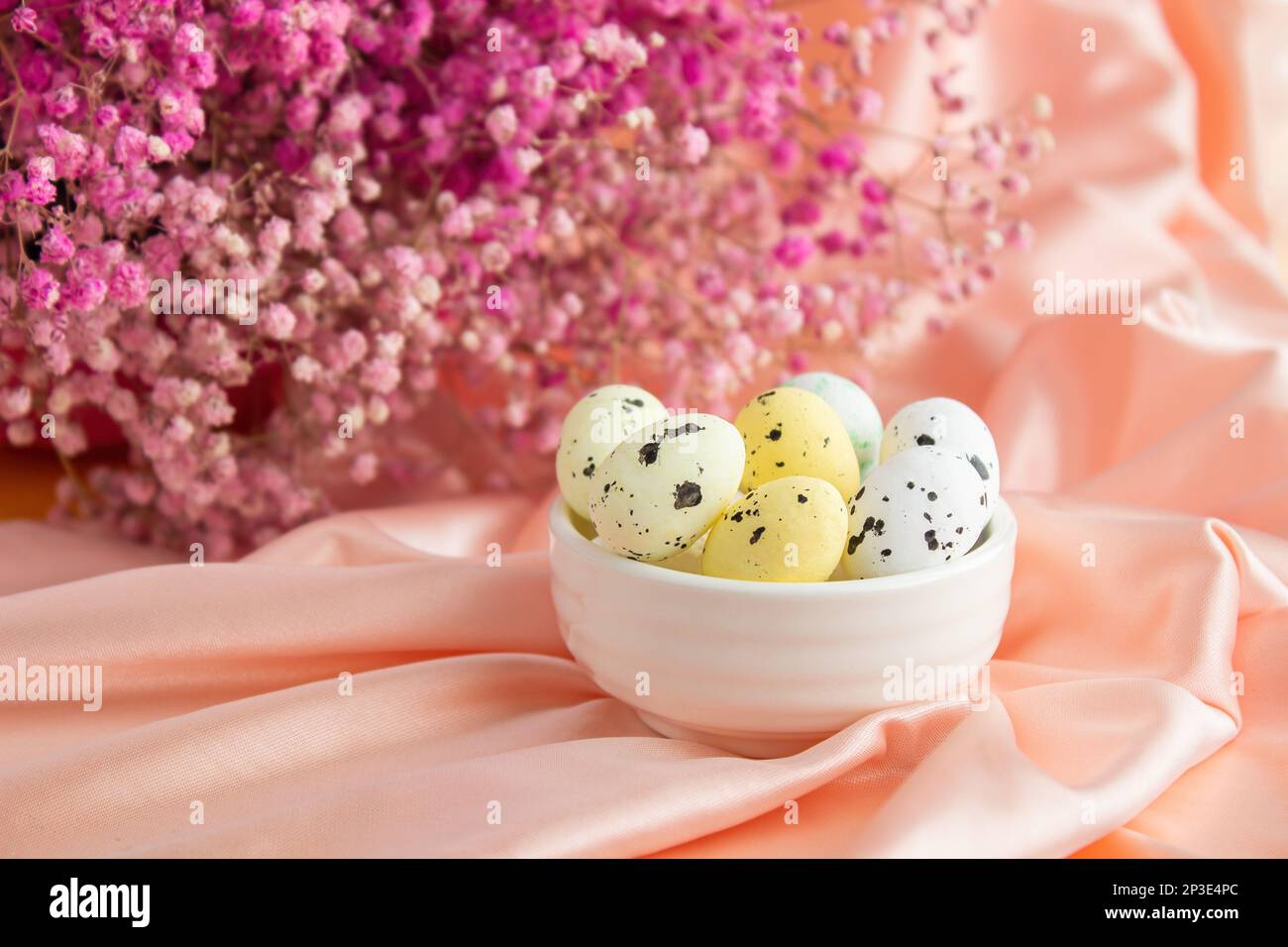 Easter composition on a background of pink satin quail eggs in a white ...