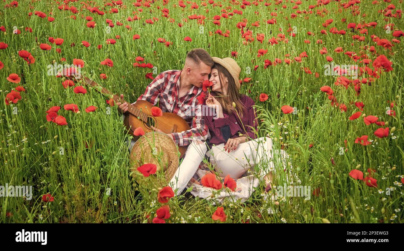 couple in love of man and woman with acoustic guitar in summer poppy ...