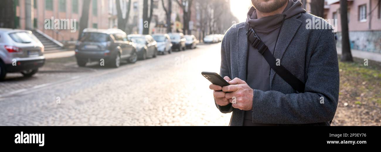 Male person using his mobile phone waiting a taxi Stock Photo - Alamy