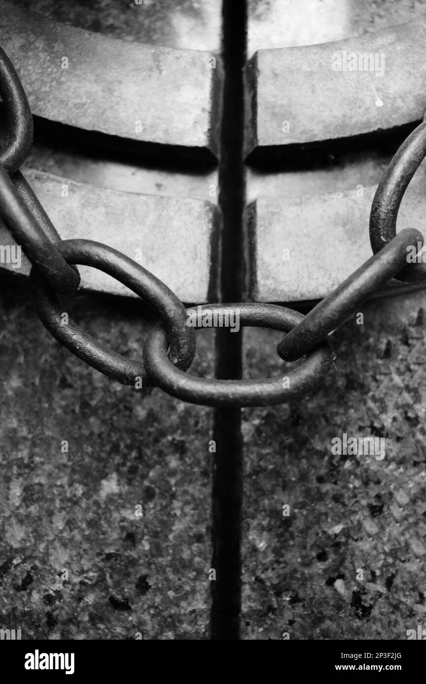 An iron metal chain hanging on the medieval gate in a black and white ...