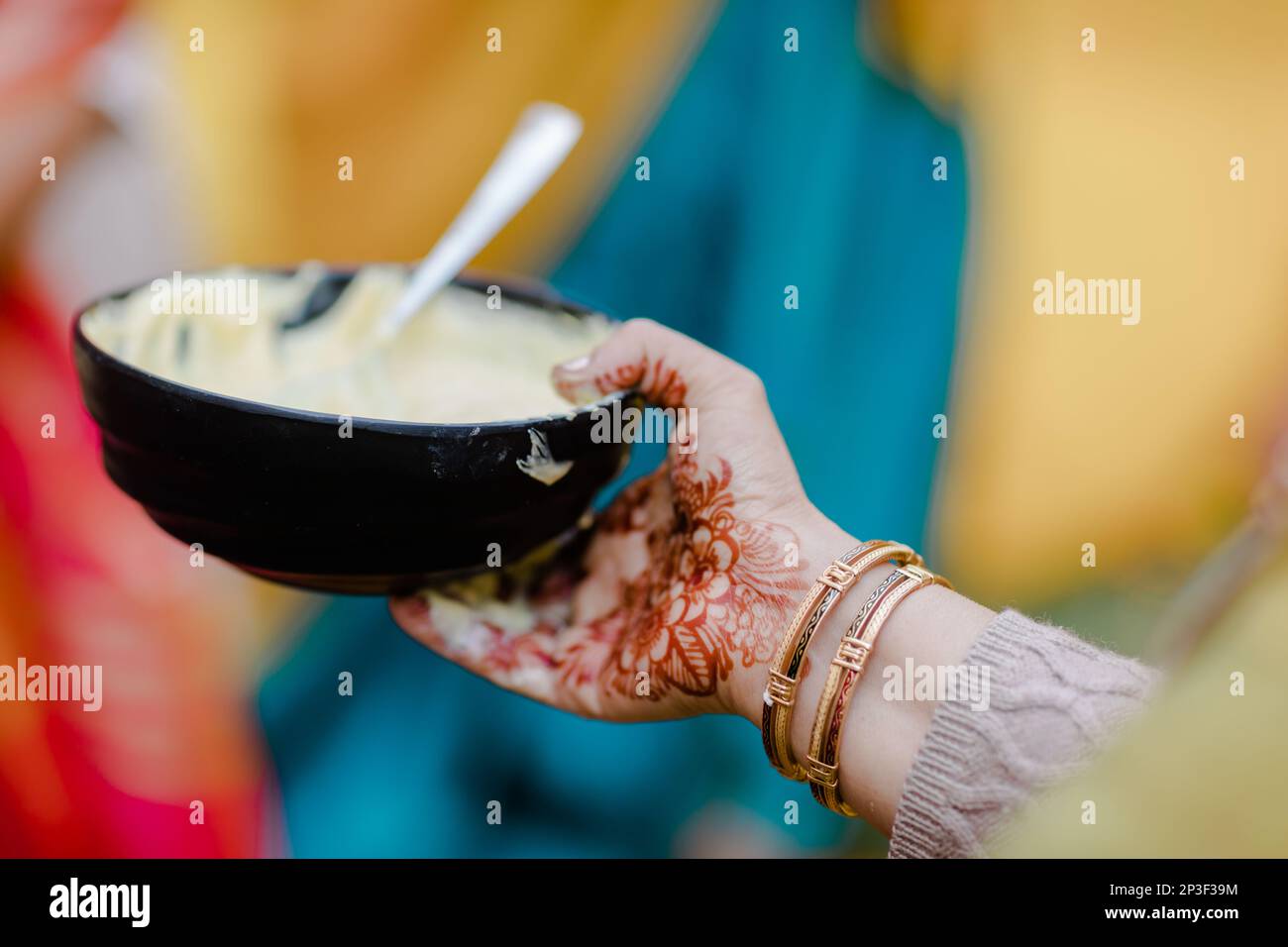 A female hand with hanna tattoos holding a turmeric paste to later ...