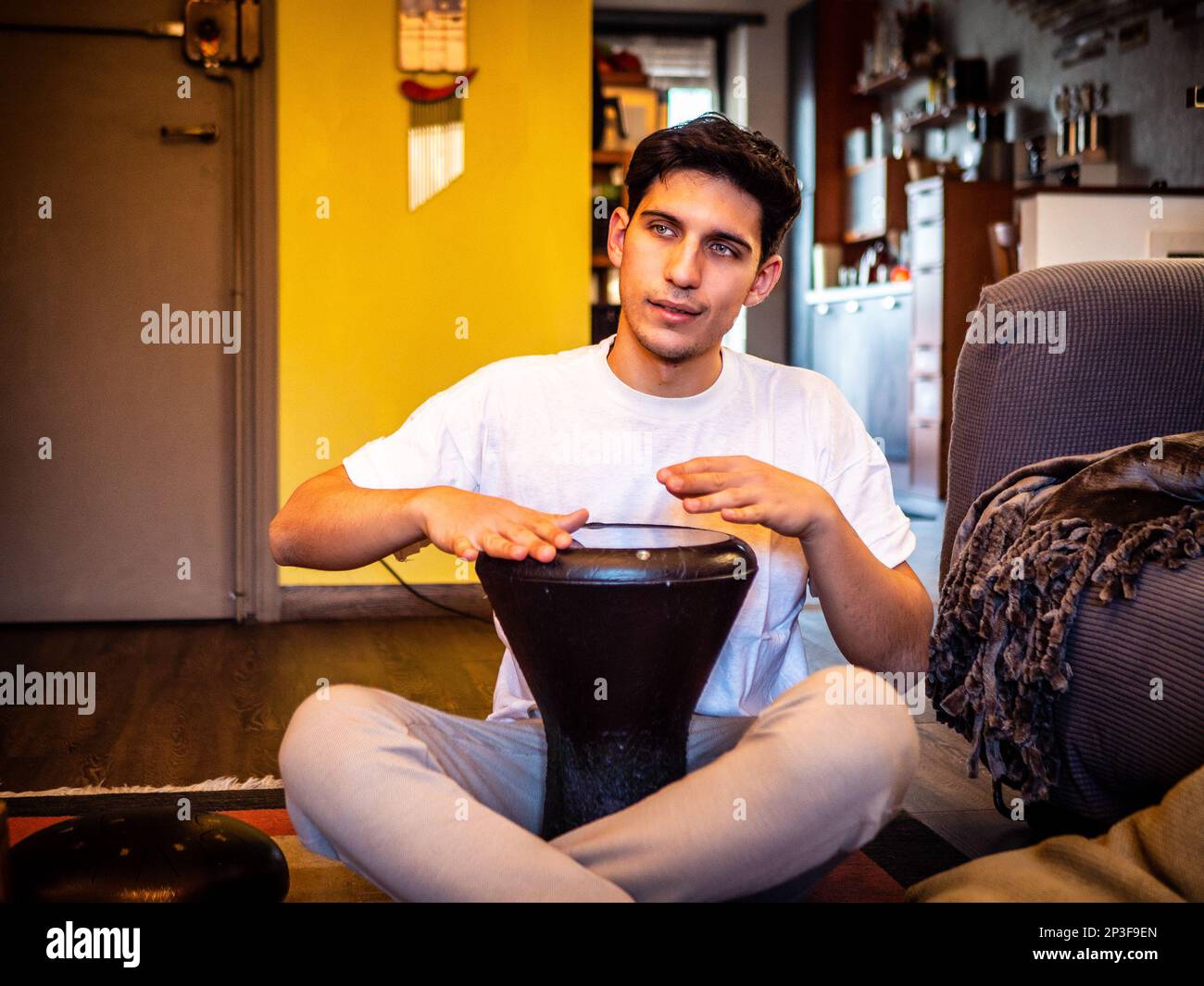 Young man playing bongo drum at home Stock Photo - Alamy