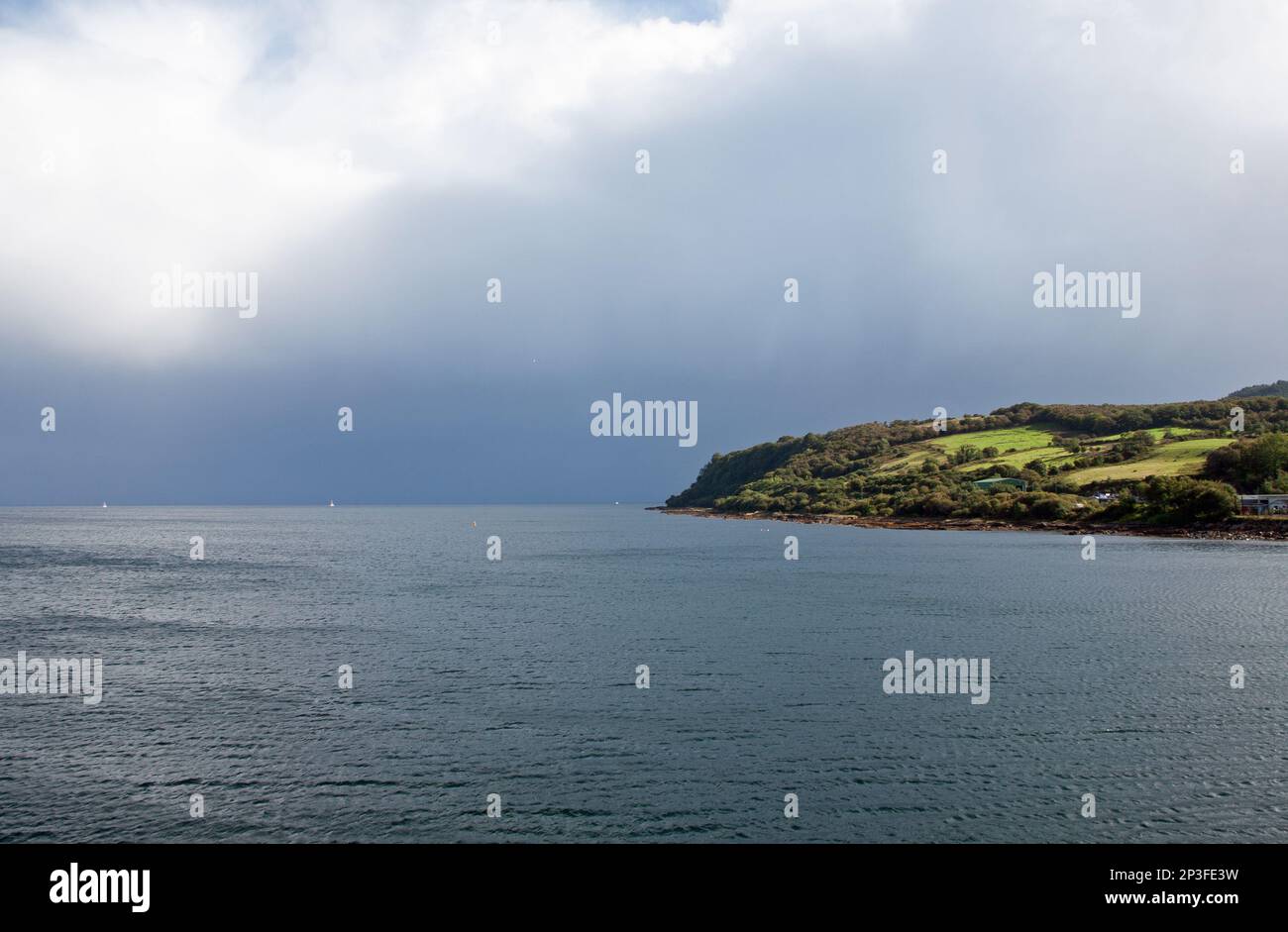 Sunlight catching the wooded coastline near Brodick Ferry Terminal from ...