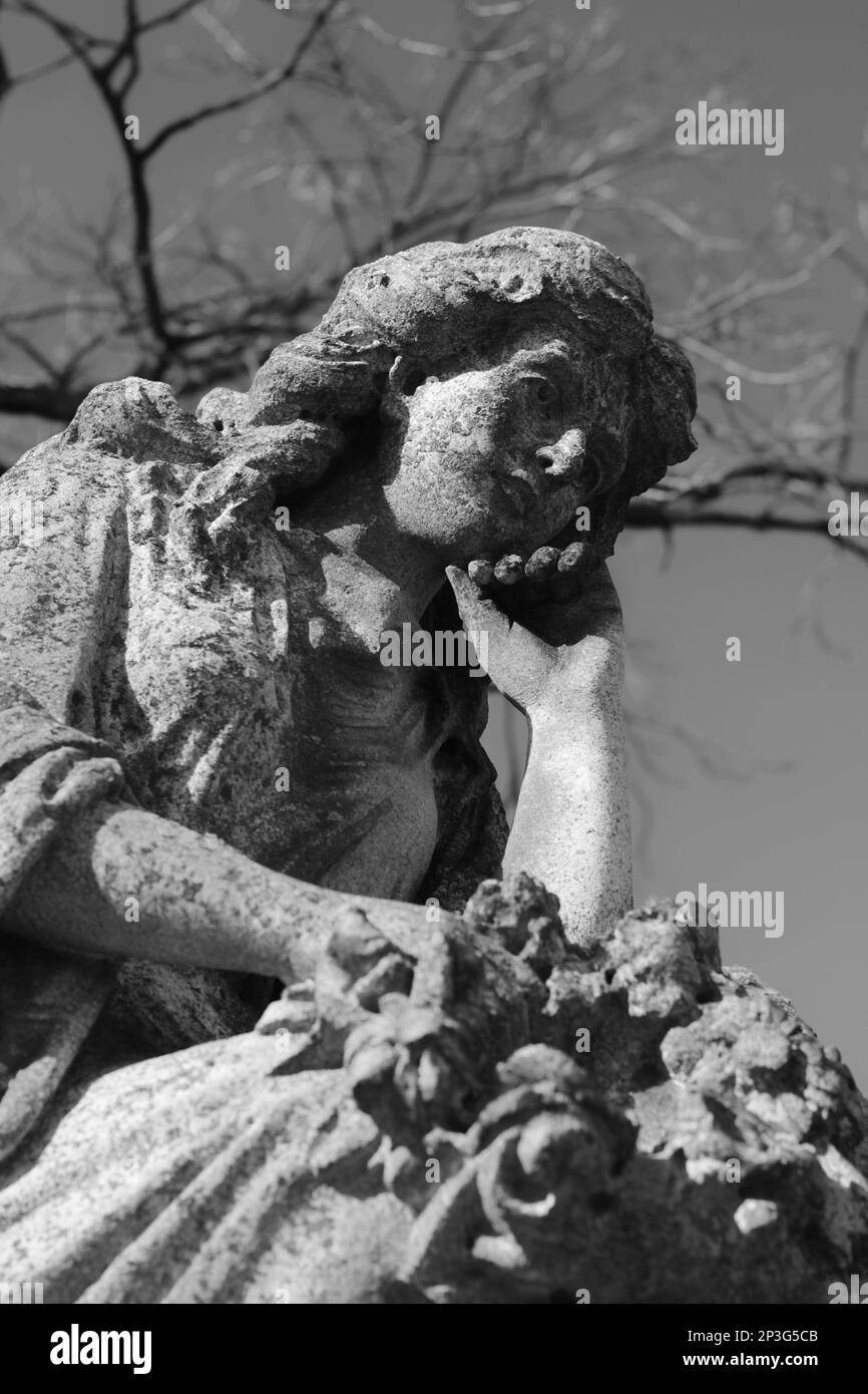 A grieving young woman carved into a natural stone statue in a black ...