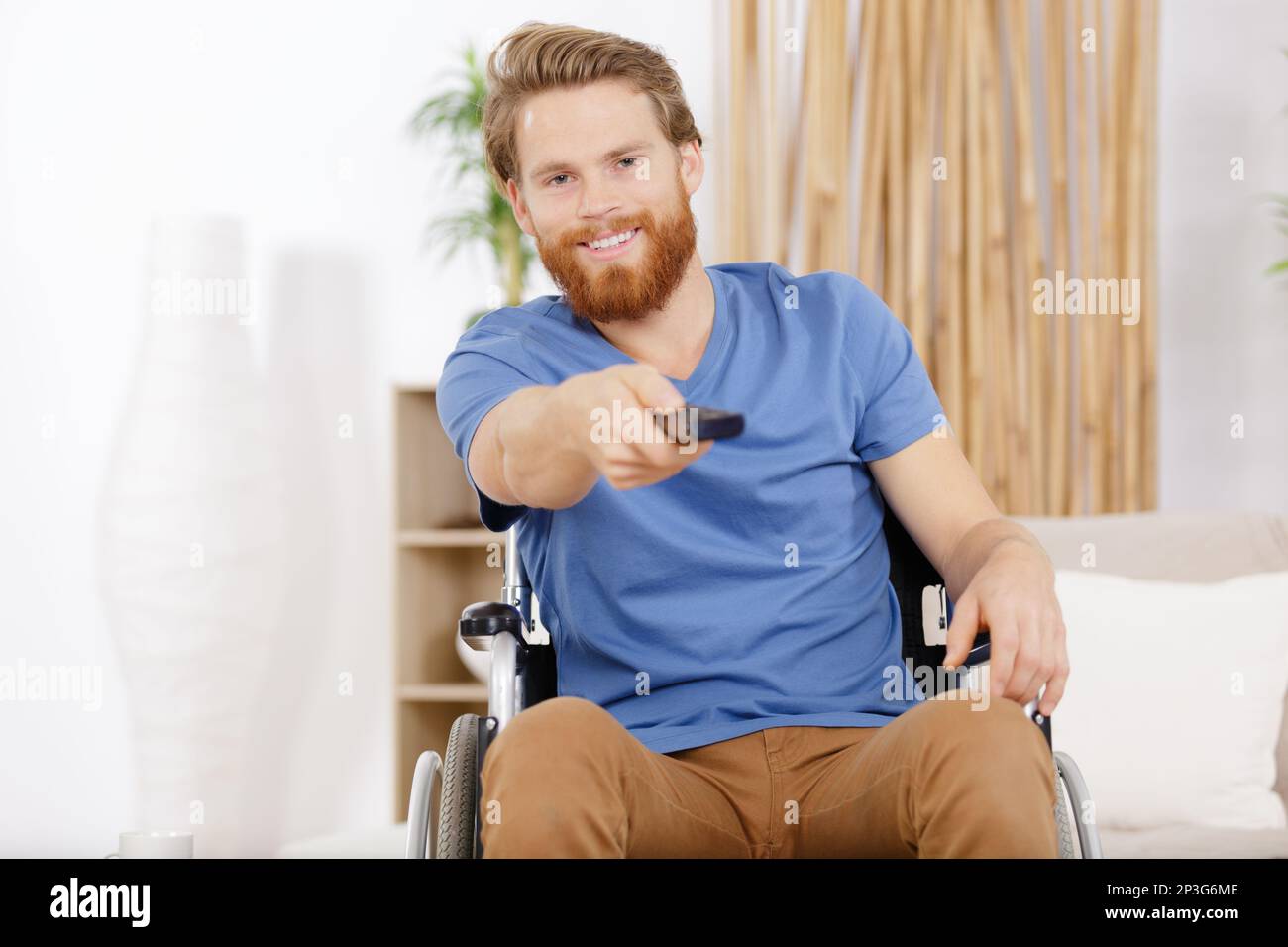 man in wheelchair using the remote control Stock Photo - Alamy