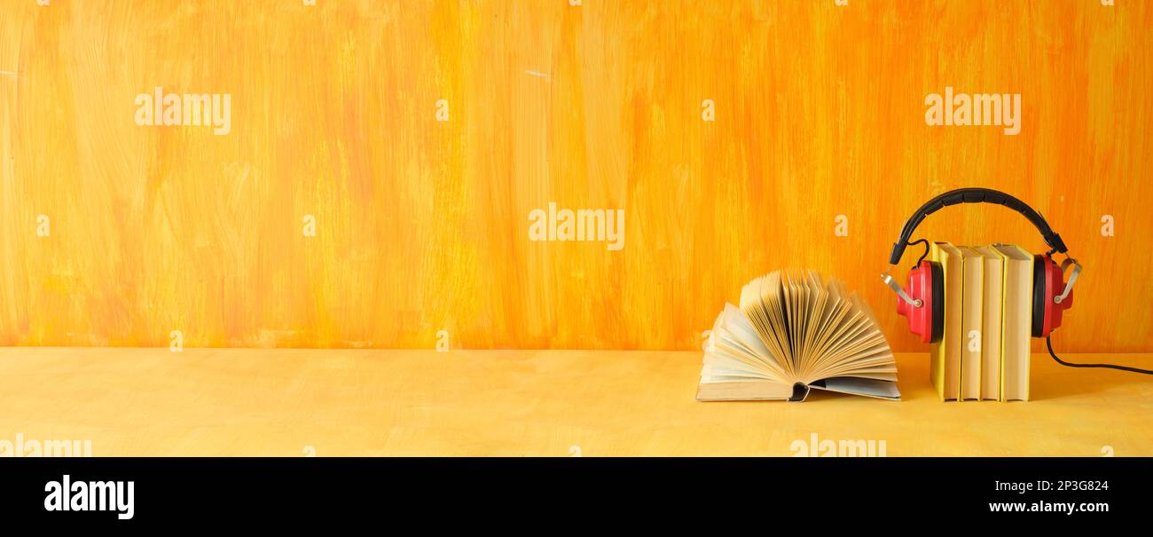 audio book concept with row of books, one opened and vintage headphones ...