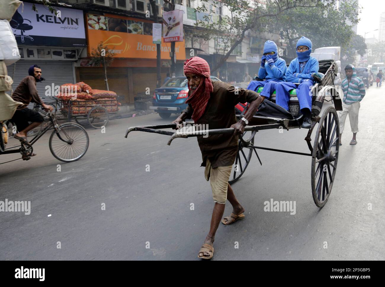 An Indian hand rickshaw puller transports children to school in Kolkata ...