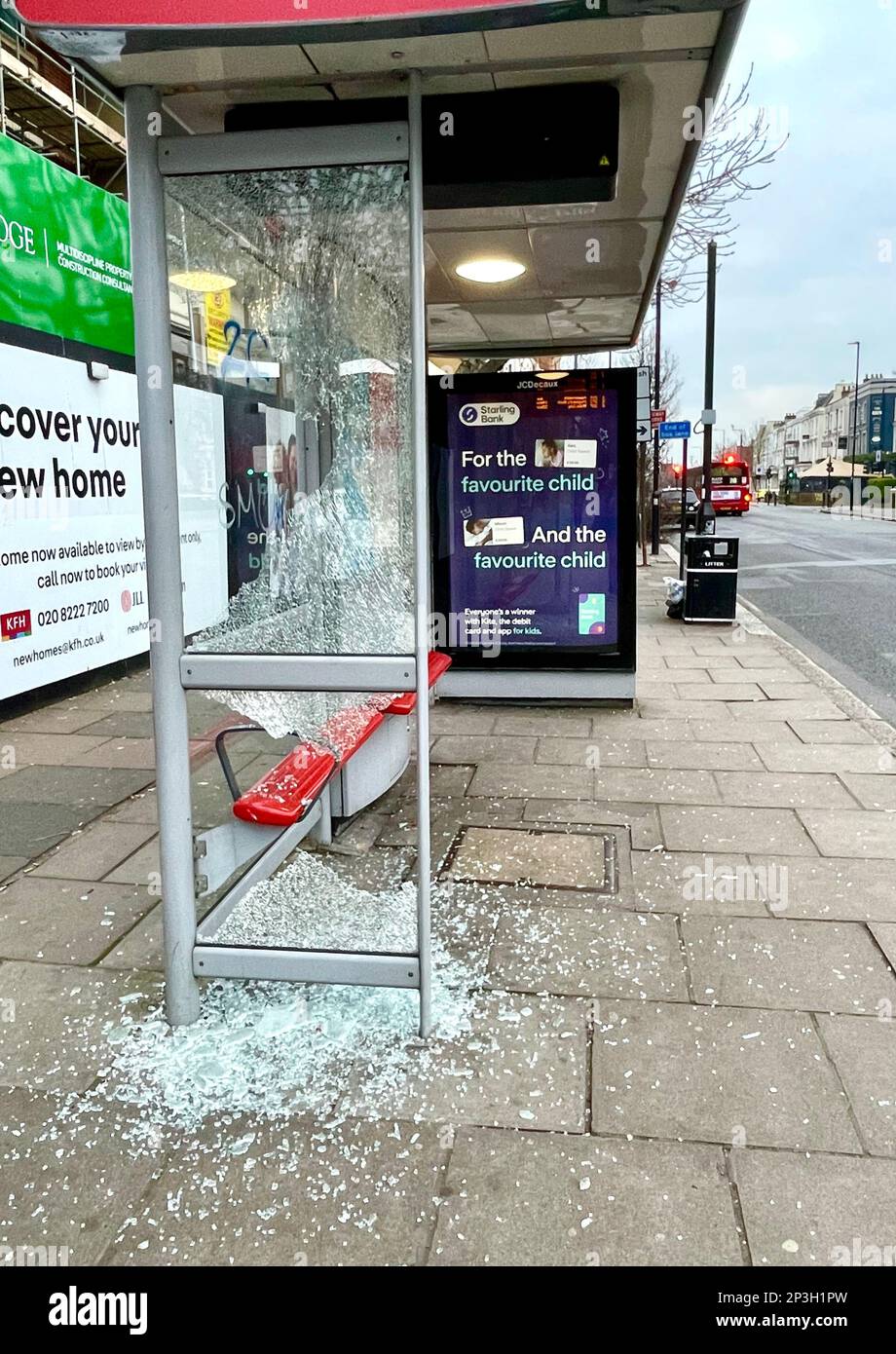 A vandalised bus shelter in Acton Town London. Broken glass lies on the ...