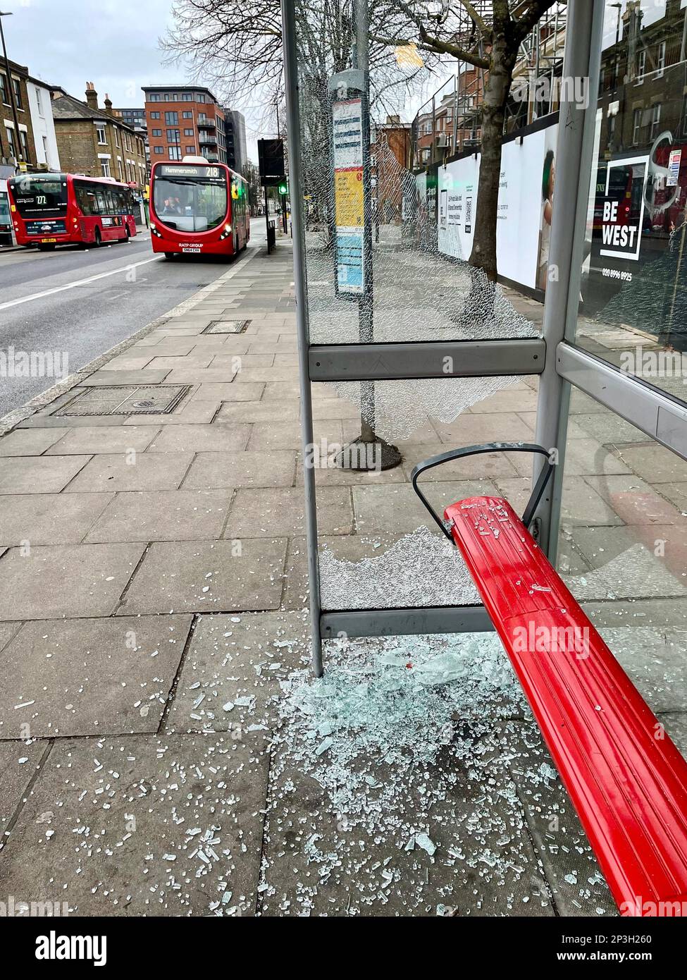 A vandalised bus shelter in Acton Town London. Broken glass lies on the ...