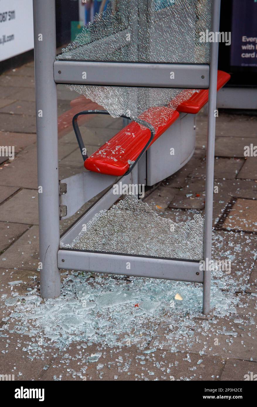 A vandalised bus shelter in Acton Town London. Broken glass lies on the ...