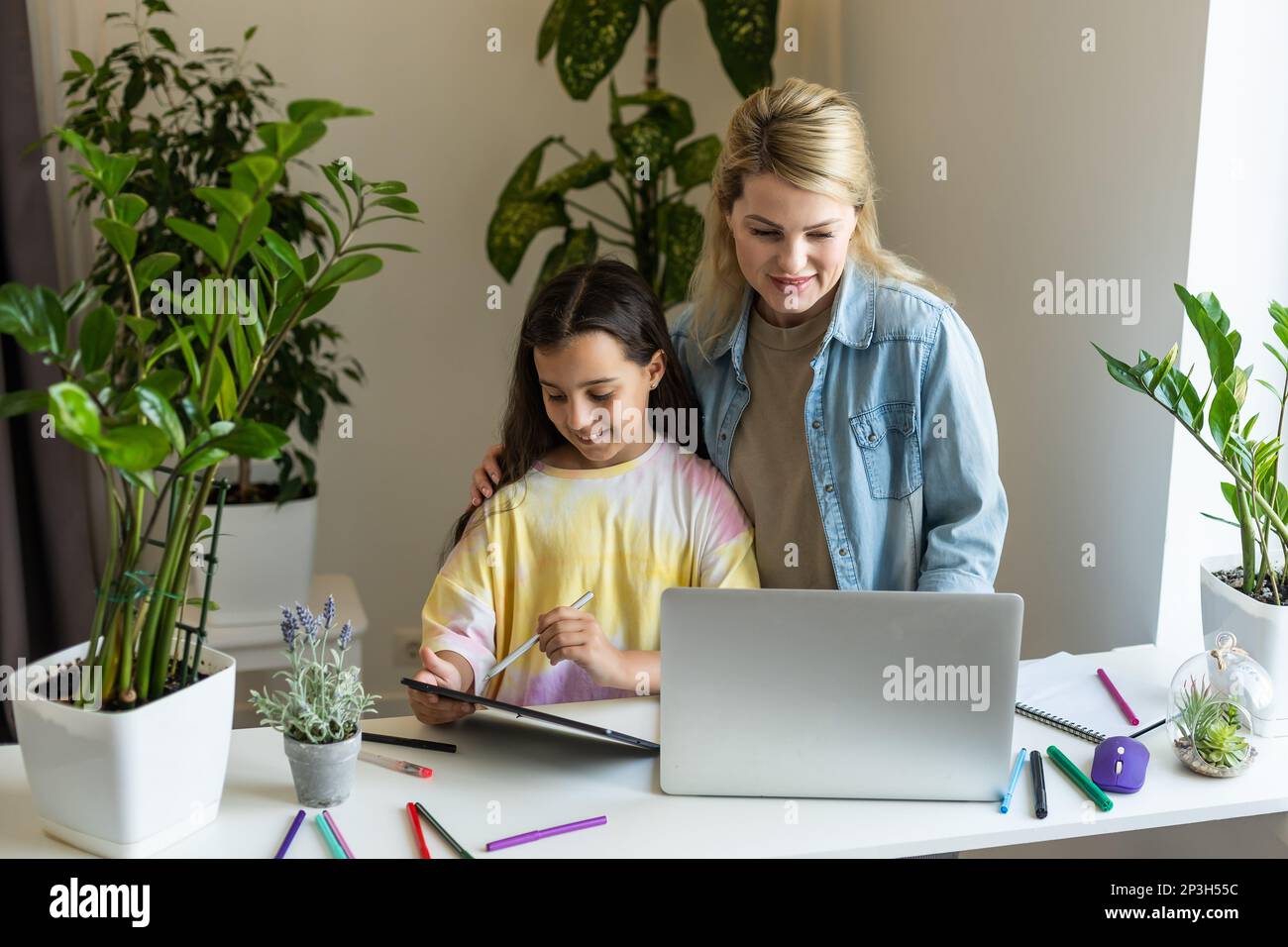 Back to school. Happy child and adult are sitting at desk. Girl doing ...