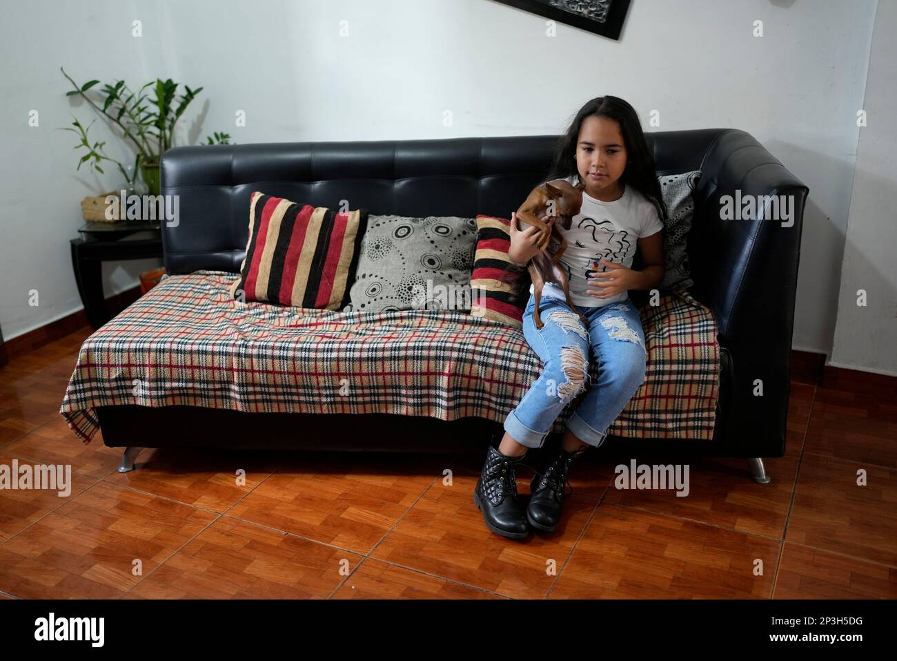 Valerie Torres holds her dog while sitting on a sofa at her home in ...