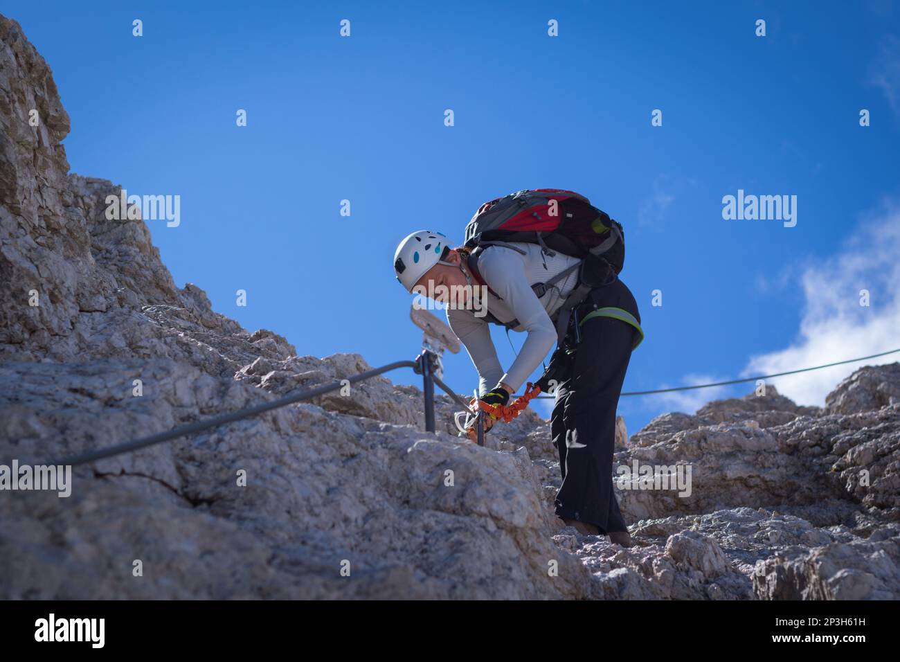 Tourist crossing the via ferrata trail with equipment in the dolomites ...