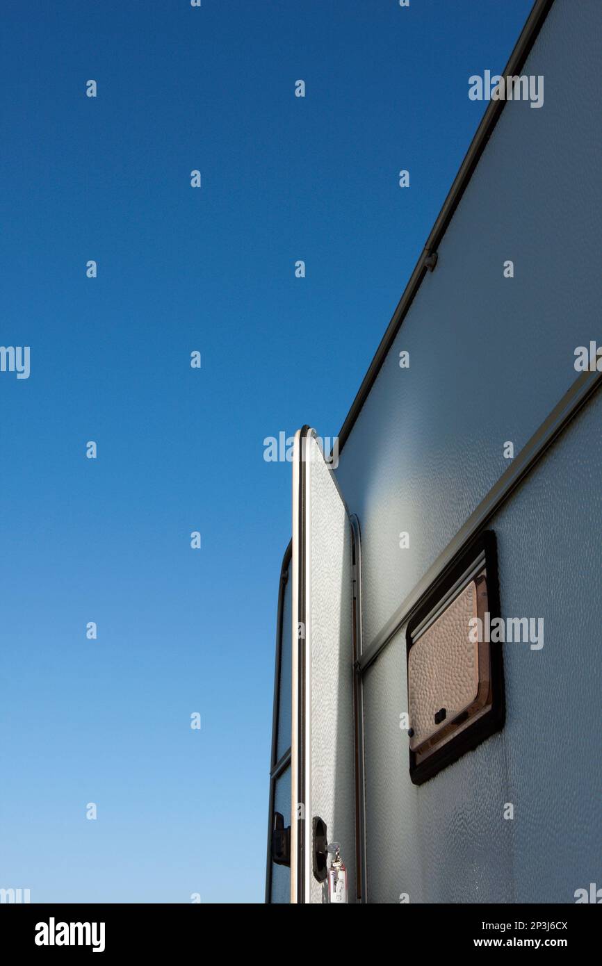 Caravan flank in the sunshine. Door, window, and bright blue sky. White ...