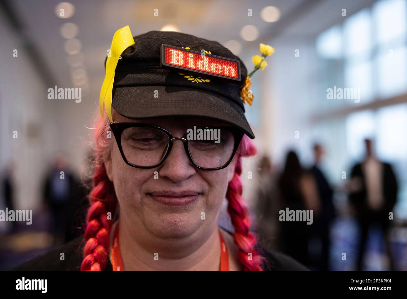Attendee Suzanne Monk wears a device with scrolling text criticizing ...