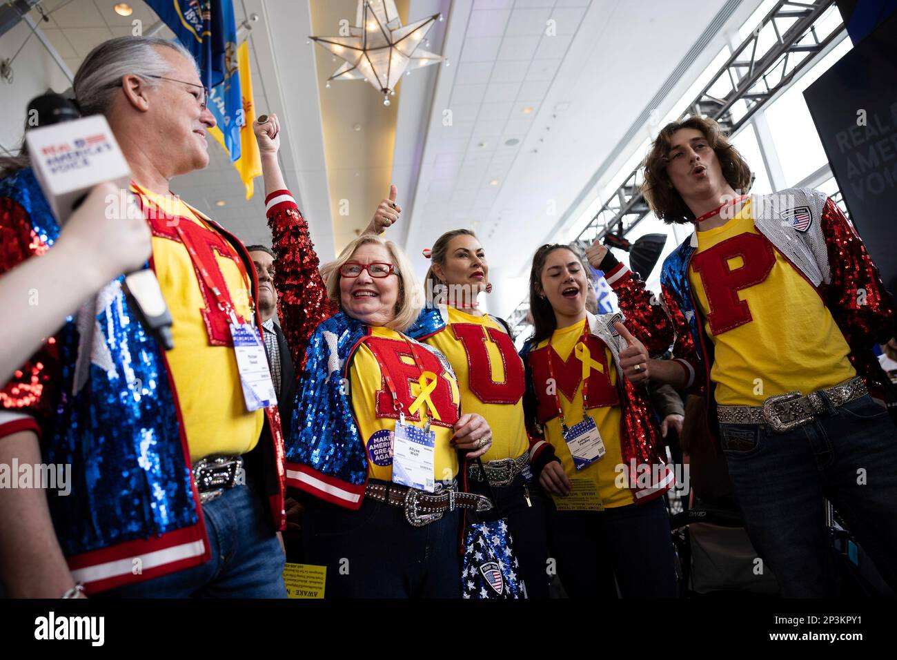 Five people with shirts spelling out "TRUMP" are seen at the ...