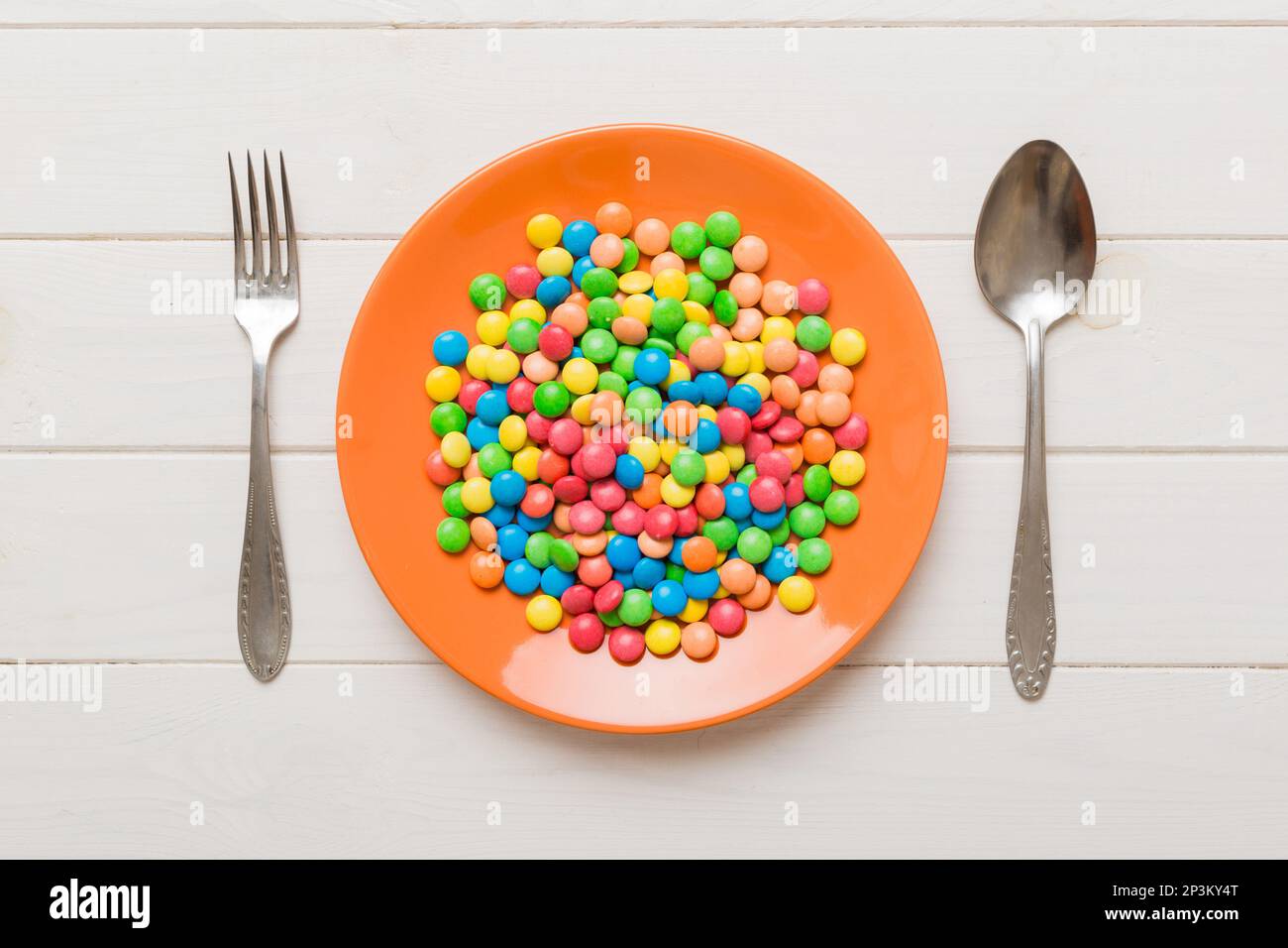 cutlery on table and sweet plate of candy. Health and obesity concept ...
