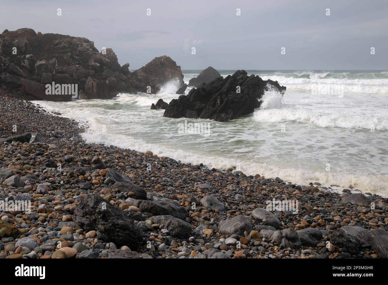 Stormy Atlantic Ocean waves breaking onto the pebble beach and rocks at ...