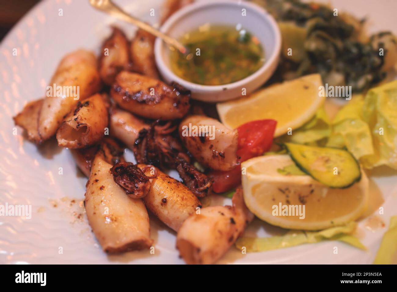 Fried grilled baby squids on a plate with garlic, lemon and mashed ...