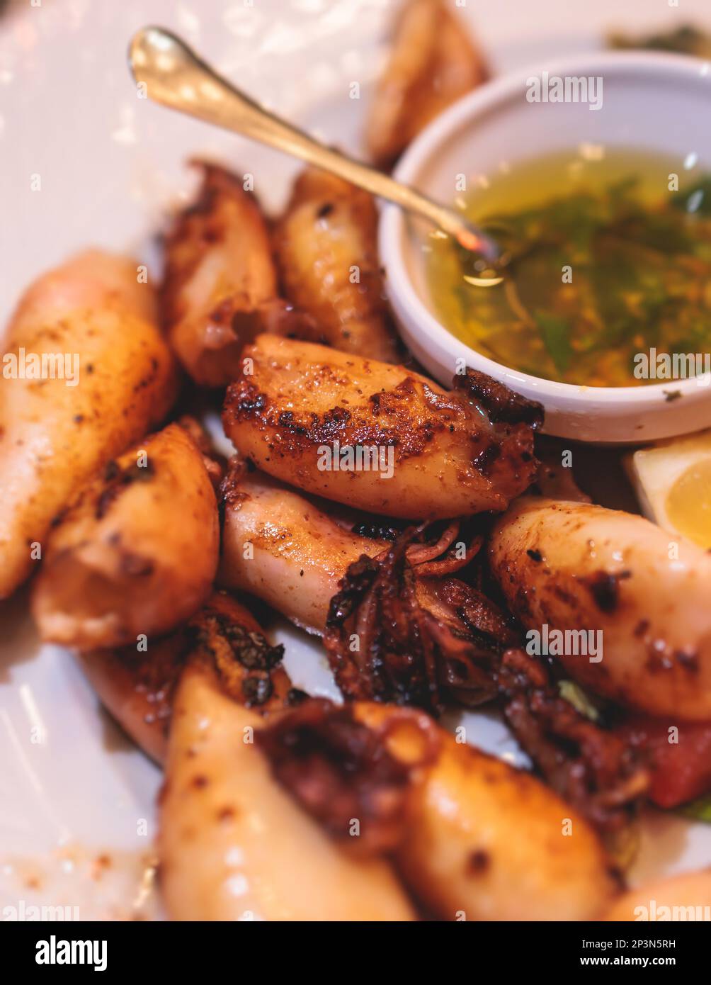 Fried grilled baby squids on a plate with garlic, lemon and mashed ...