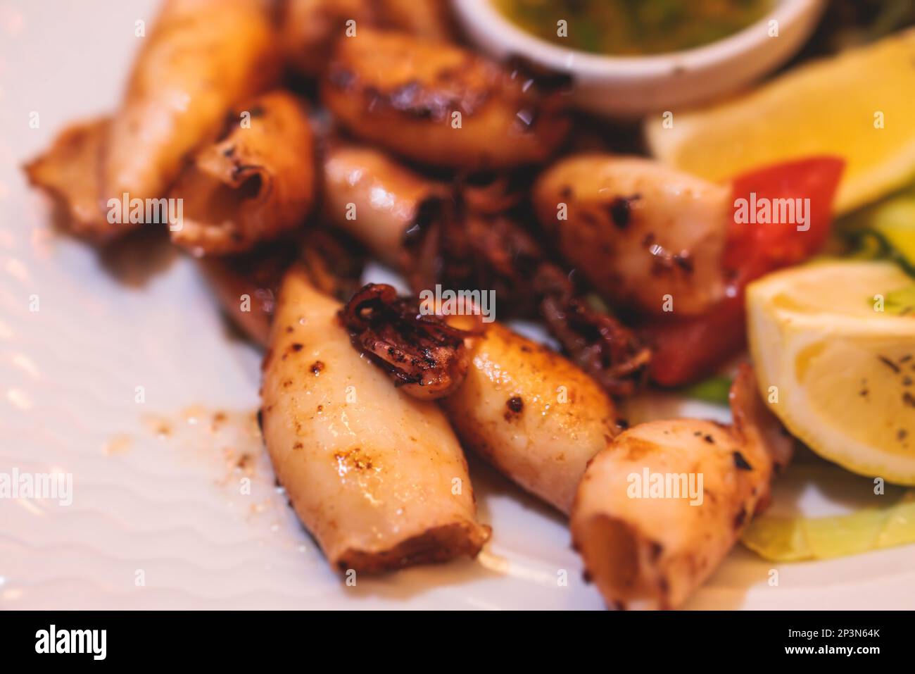 Fried grilled baby squids on a plate with garlic, lemon and mashed ...