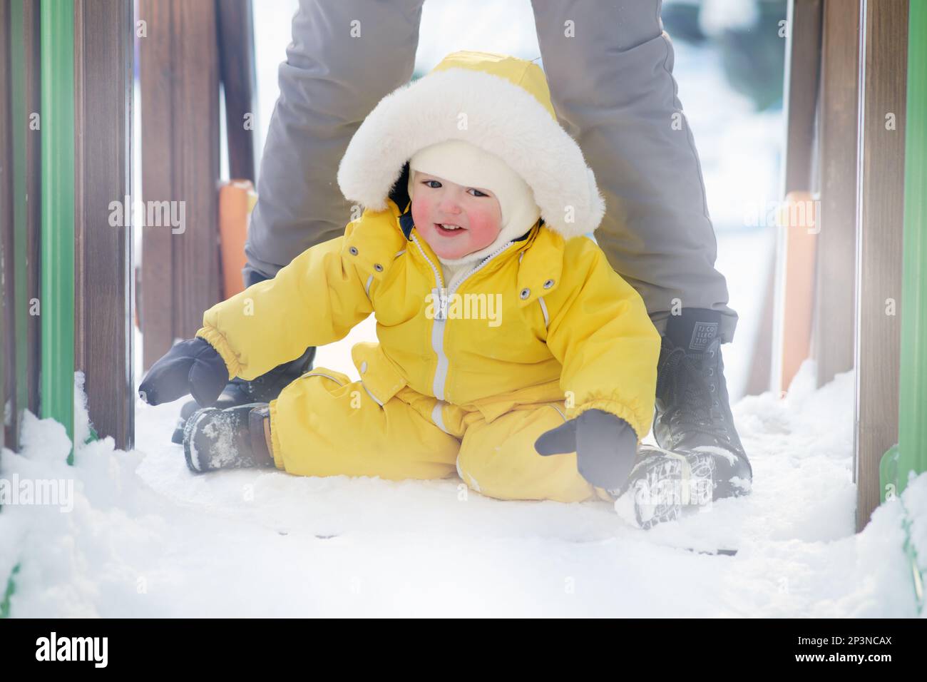 Toddler baby boy is playing in the snow on the winter playground. Happy ...