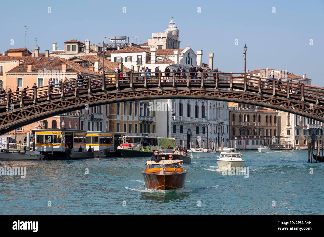 Water taxis and small boats pass under the Accademia bridge on the ...