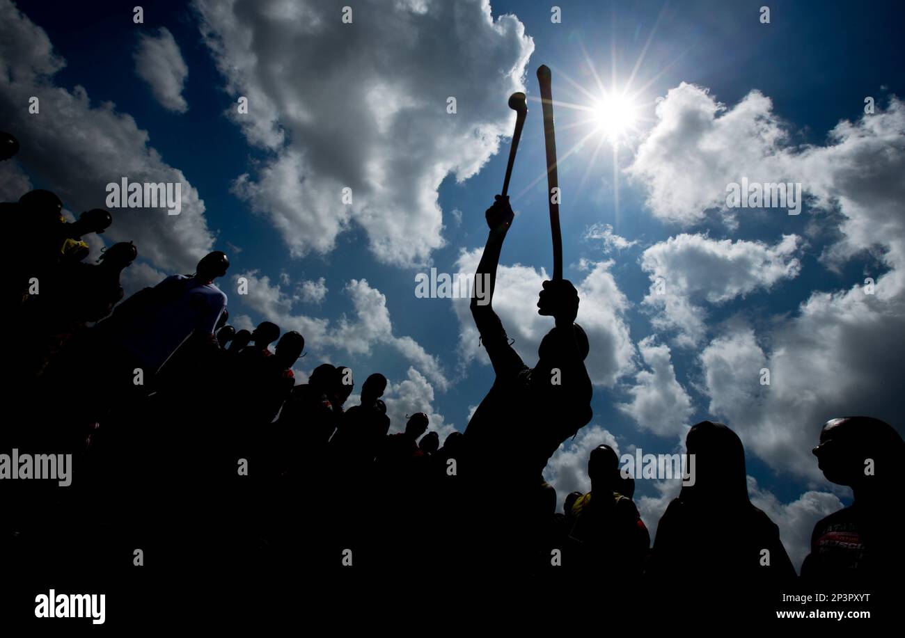 A Maasai warrior holds up his stick to line his sight, right, as he ...