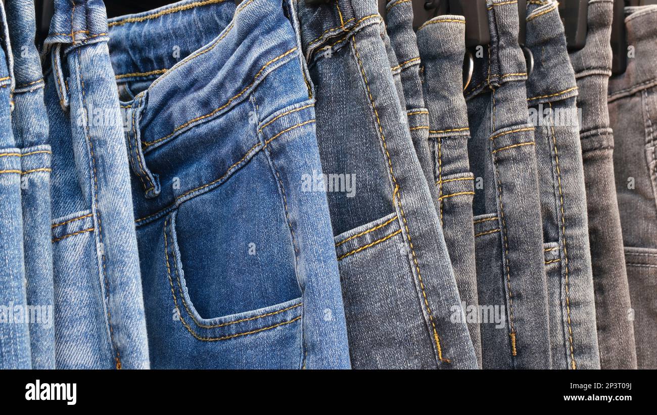 Many jeans hanging on arack. Row of pants denim jeans hanging in closet ...