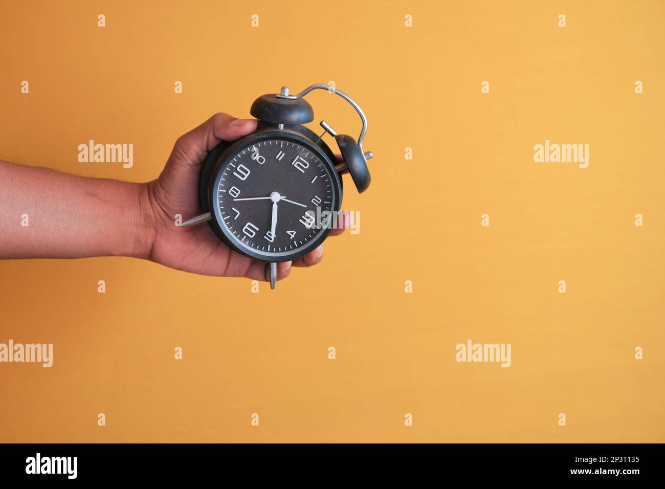 person hand holding alarm clock white background Stock Photo - Alamy
