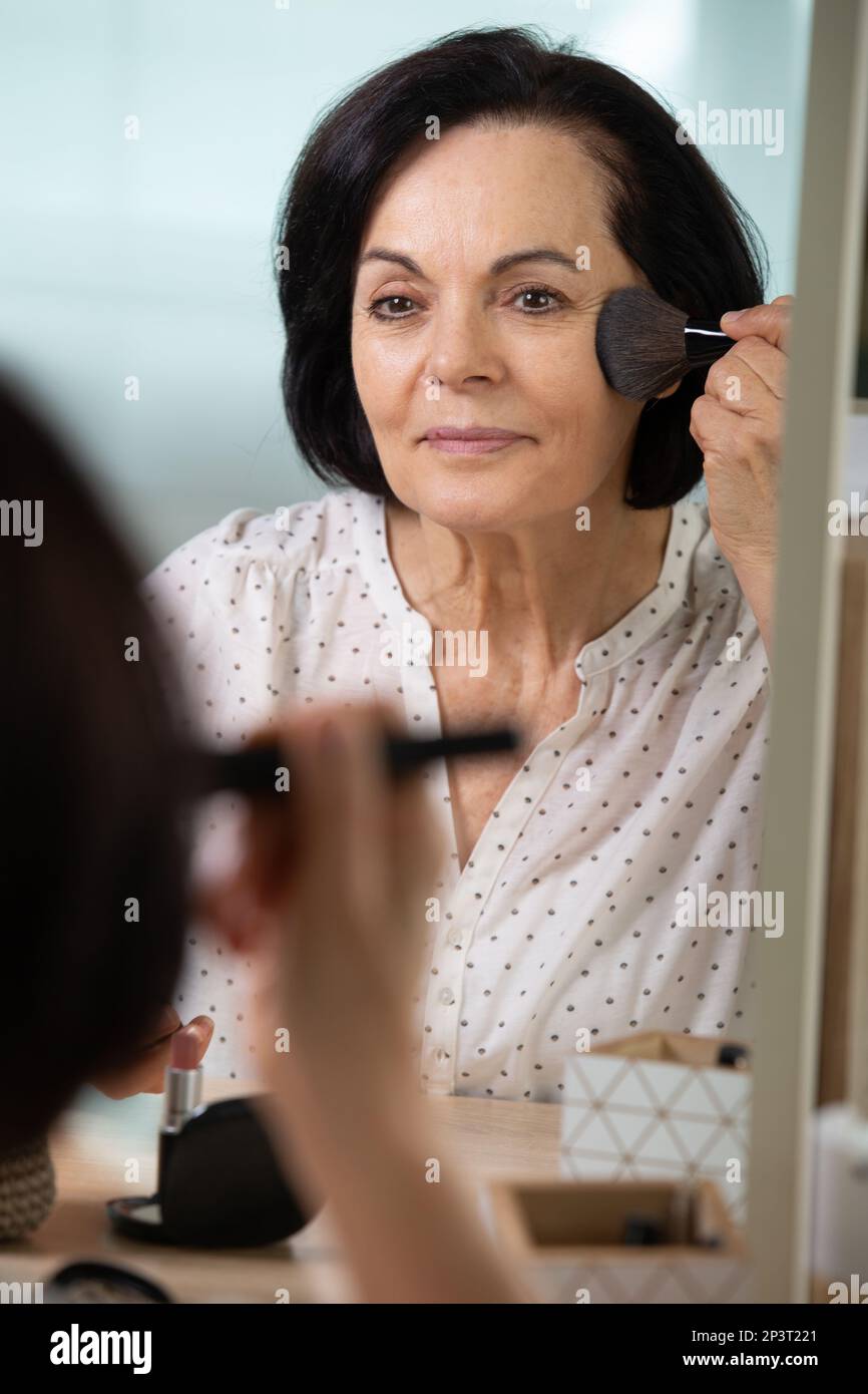 Mature woman applying face powder hi-res stock photography and images ...