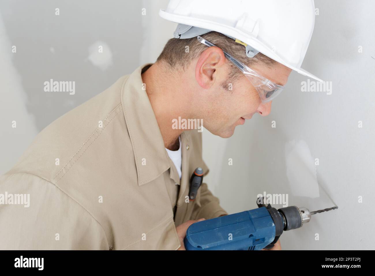 man drilling the wall with drill perforator Stock Photo - Alamy