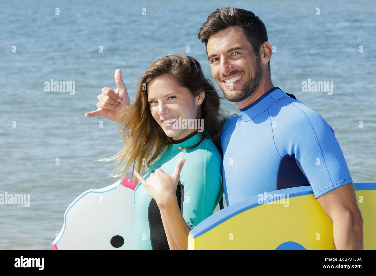 surfing couple making shaka hand gesture Stock Photo - Alamy