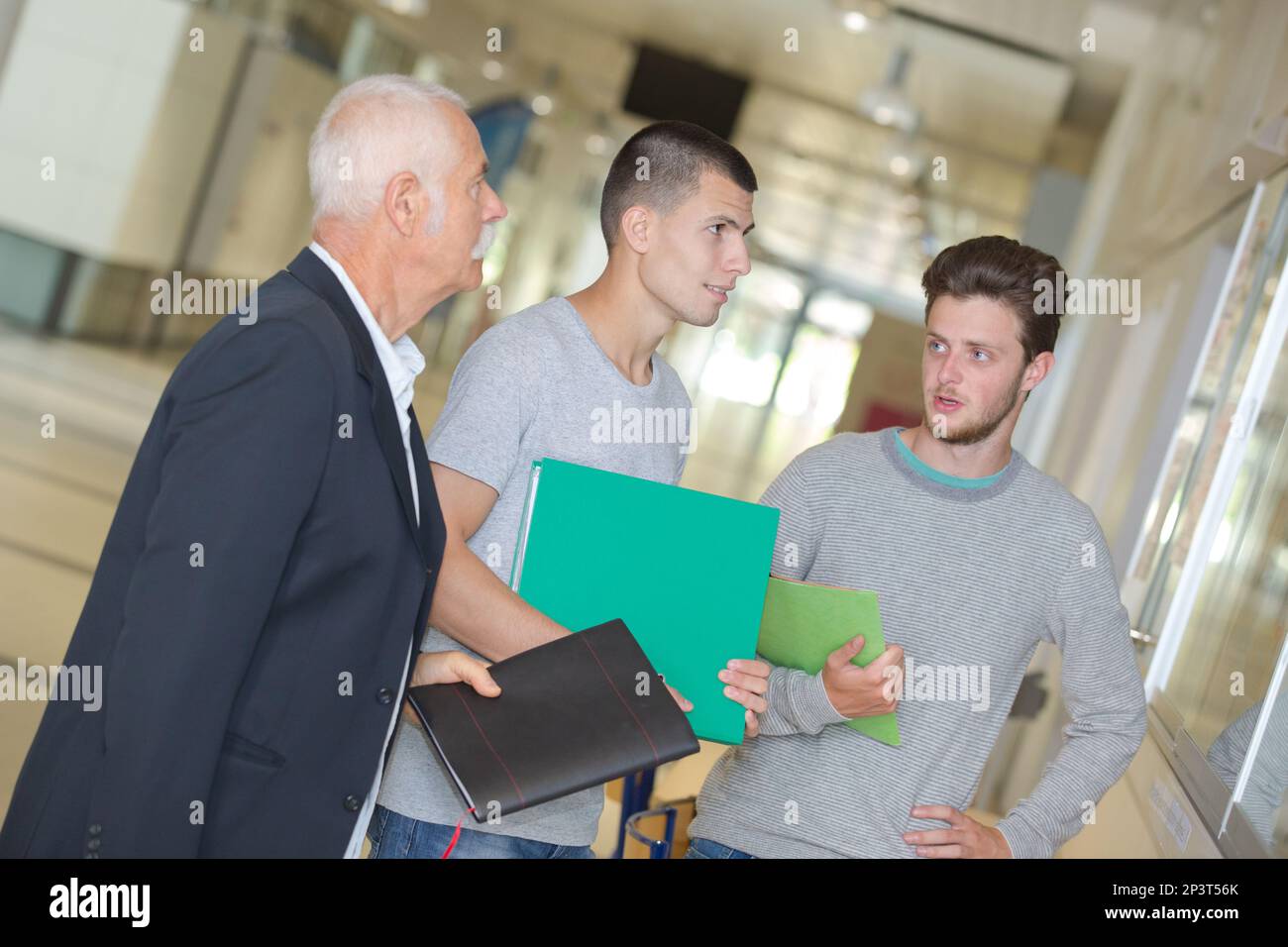 two students stood with teacher by notice boards Stock Photo - Alamy