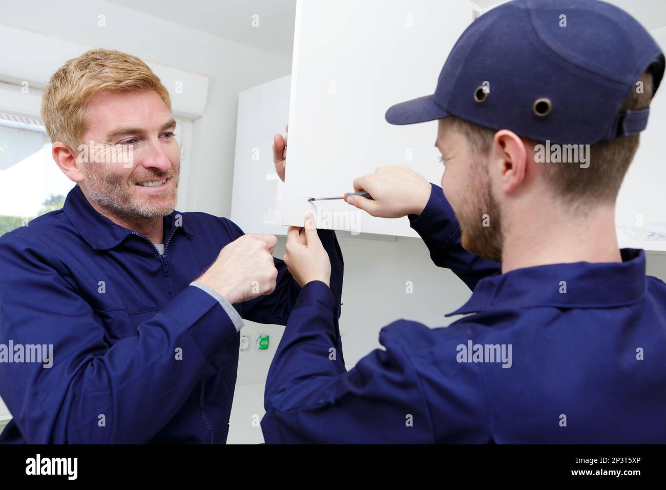two carpenters workers joint and settle home built-in cupboard Stock ...